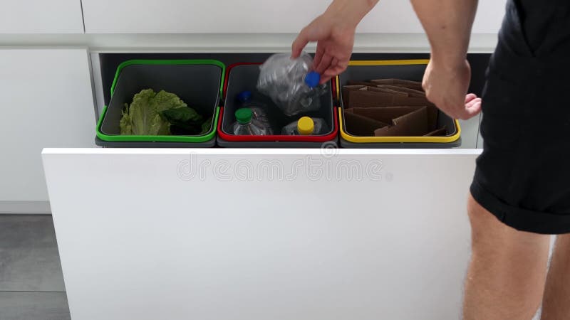A Young Man Sorts Garbage in Containers in the Kitchen. Modern Kitchen ...
