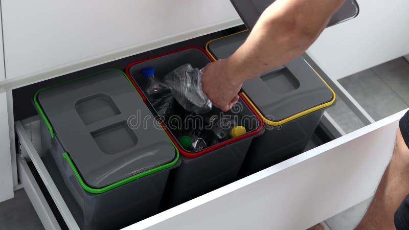 A Young Man Sorts Garbage in Containers in the Kitchen. Modern Kitchen ...