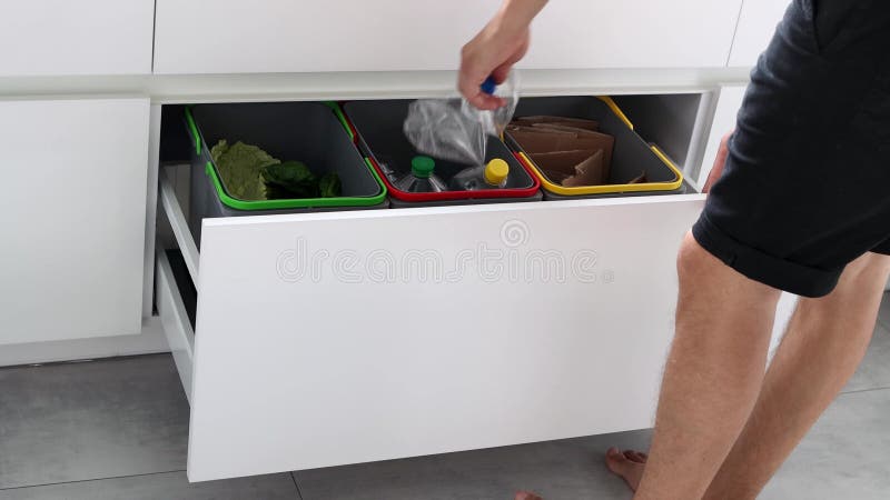 A Young Man Sorts Garbage in Containers in the Kitchen. Modern Kitchen ...