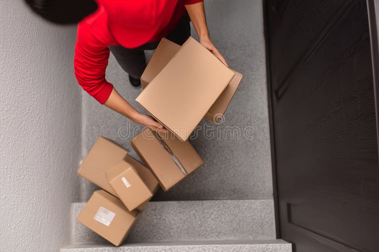 Young Man Stacking Cardboard Boxes on Doorstep in Urban Setting. Clean Grey Steps Provide a ...