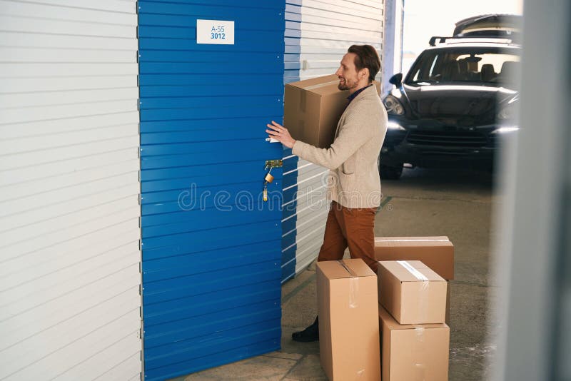 Side View of Guy with Big Cardboard Boxes in Self Storage Unit Stock ...