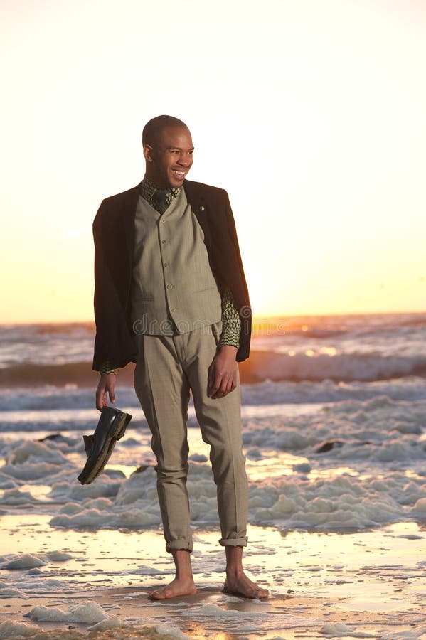 Young Man Standing on the Beach with Shoes in Hand Stock Image - Image ...