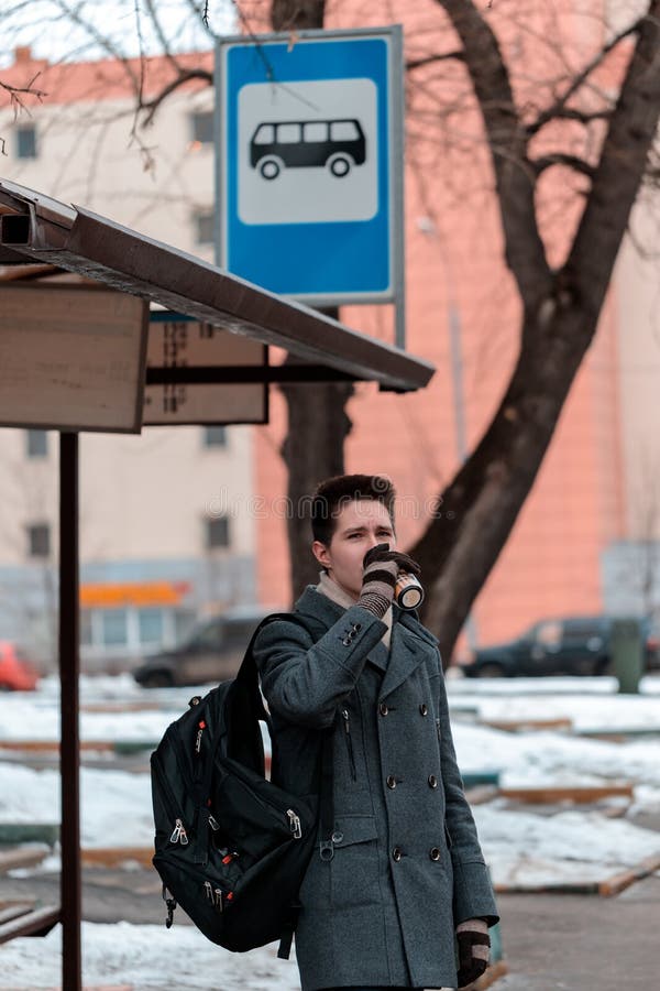 A Young Man is Standing at the Bus Stop and Waiting for the Bus Stock ...