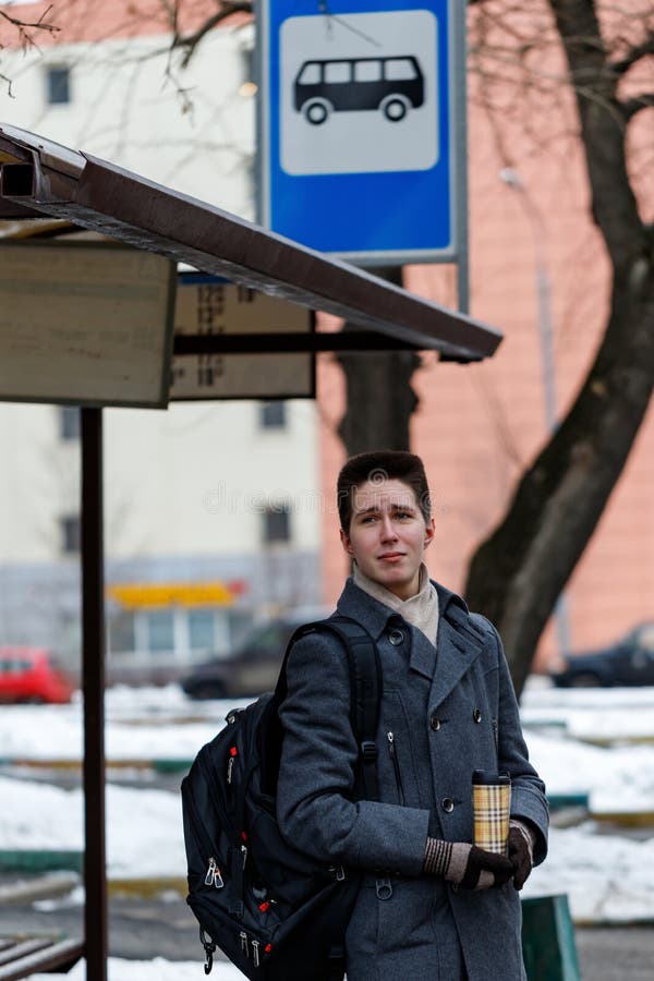 A Young Stylish Man in a Coat, a Traveler or a Student, with Headphones ...