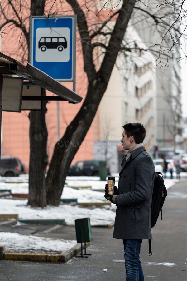 A Young Stylish Man in a Coat, a Traveler or a Student, with Headphones ...