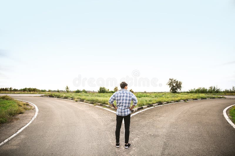 Young Man Standing at Crossroads. Concept of Choice Stock Photo - Image ...