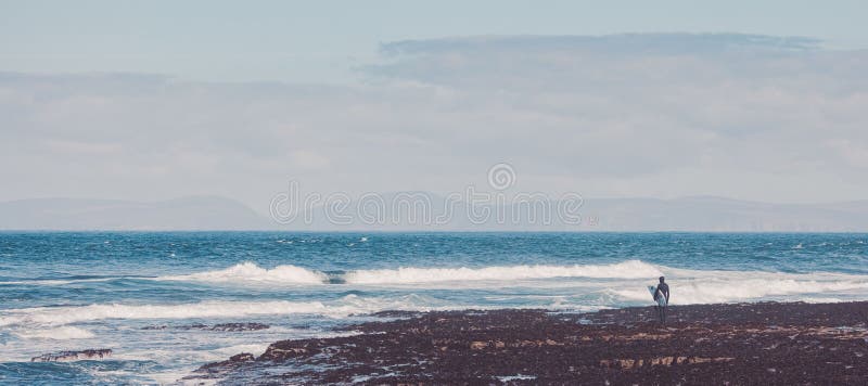 Young Man Standing on a Sandy Beach, Facing the Ocean, with a Surfboard ...