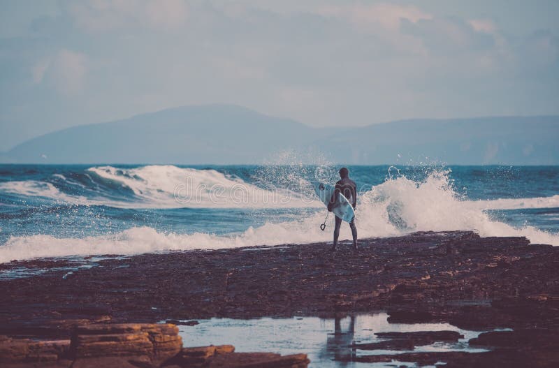 Young Man Standing on a Sandy Beach, Facing the Ocean, with a Surfboard ...