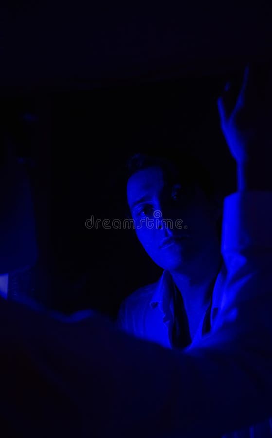 A Young Man Standing in Semi-darkness, Illuminated by Blue Light ...