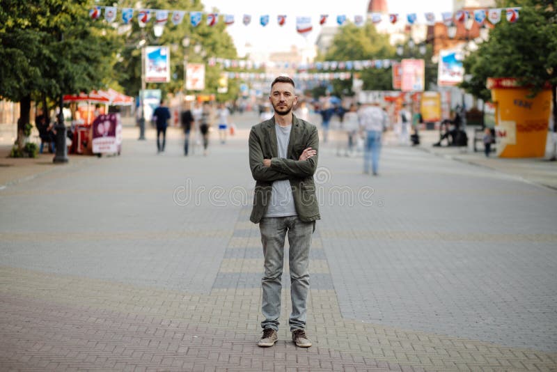 Young Man Standing Still at Sidewalk with People Moving Around Stock ...
