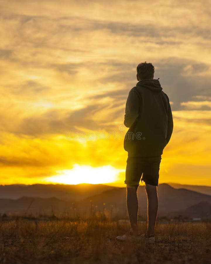 Young Man Standing on the Summit of a Hill Facing the Sunset. Stock ...