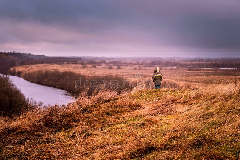A Young Man Stands on the Top of a Hill Overlooking the River Valley ...
