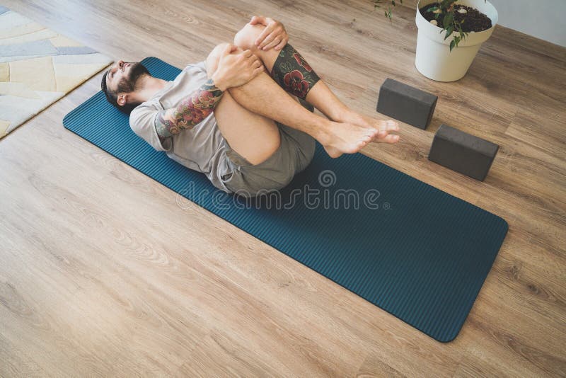 Young Man Starting the Day with Wind-Relieving Pose at Home Stock Photo ...