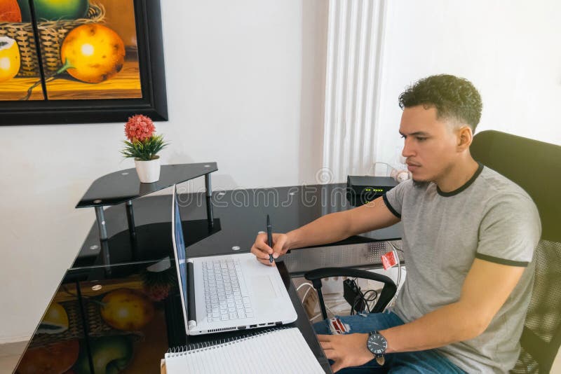 A Young Man Studying at Home with His Laptop, Taking Classes Online ...