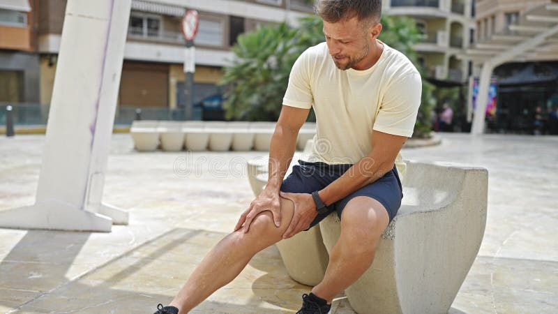 Young Man Suffering for Knee Injury Sitting on Bench at Park Stock ...