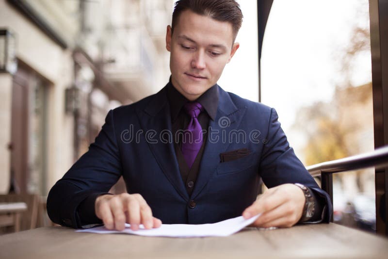 A Young Man in a Suit Reads a Document before Signing the Contract ...