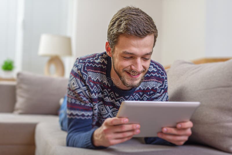 Young Man with Tablet Computer in Their Hands, on the Couch at Home ...