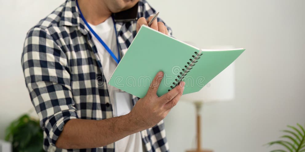 Note Taking. Young Professional Writing in a Notebook while on a Phone ...