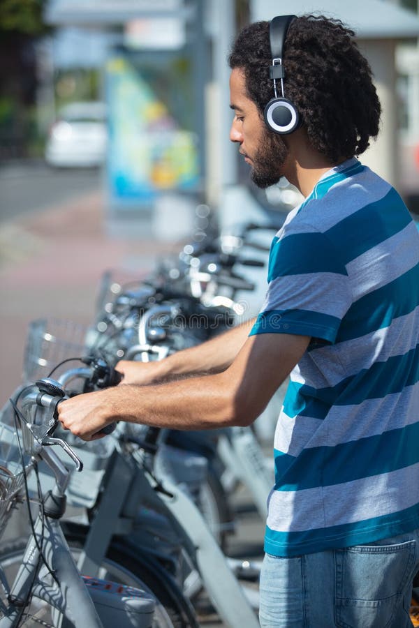Young Man Taking Bicycle from Automated Bicycle Sharing System Stock ...