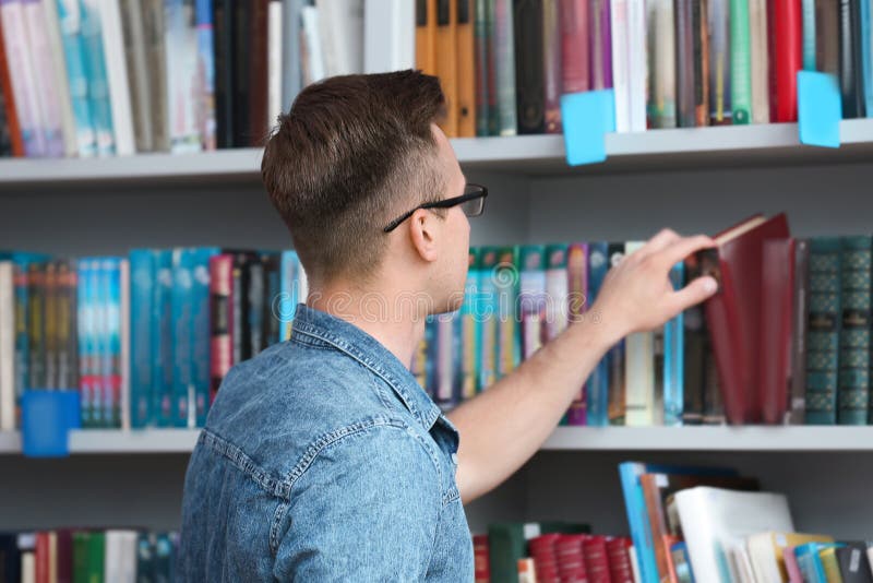 Young Man Taking Book from Shelving Unit Stock Image - Image of ...