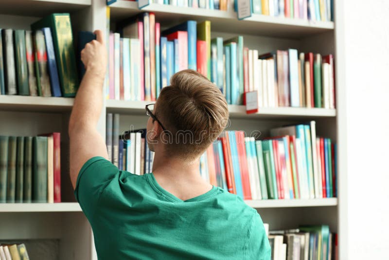 Young Man Taking Book from Shelving Unit Stock Image - Image of male ...