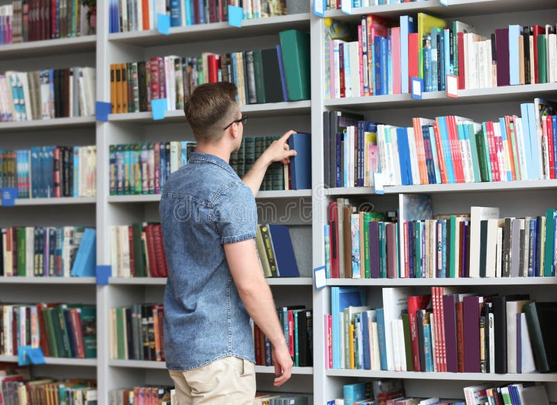 Young Man Taking Book from Shelving Unit in Library Stock Photo - Image ...