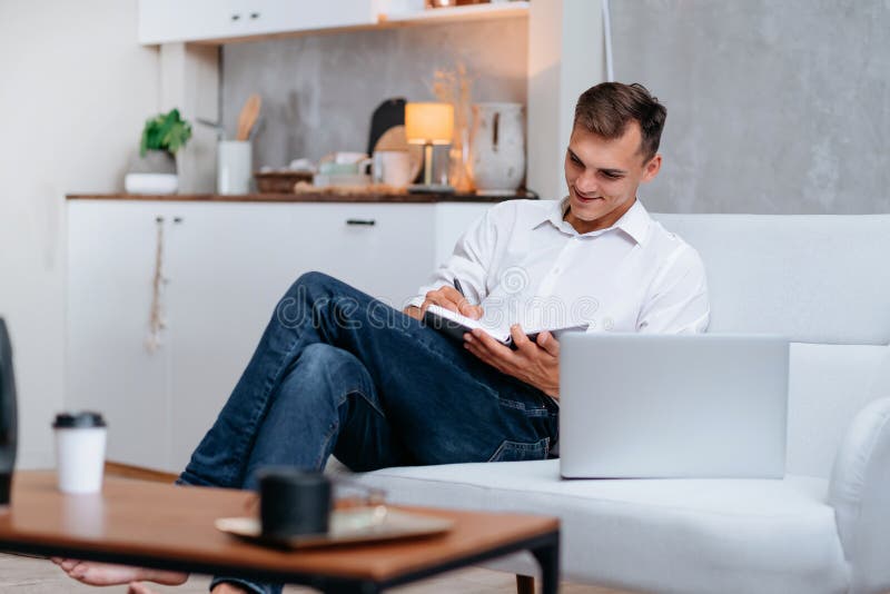 Young Man Taking Notes Sitting on the Couch . Stock Photo - Image of ...