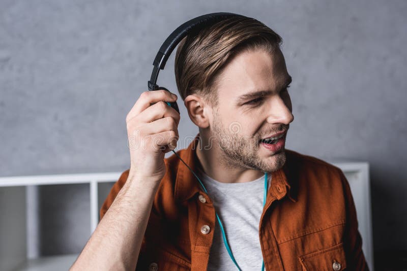 Young Man Taking Off One Headphone To Stock Photo - Image of male ...
