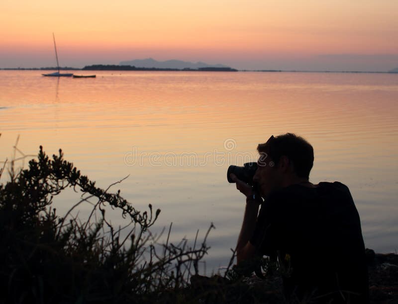 Young Man Taking a Photo with His Camera at Sunset by the Sea Stock ...