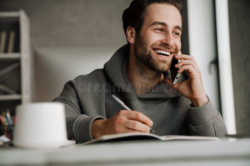Young Man Talking on Cellphone while Writing Down Notes in Planner ...