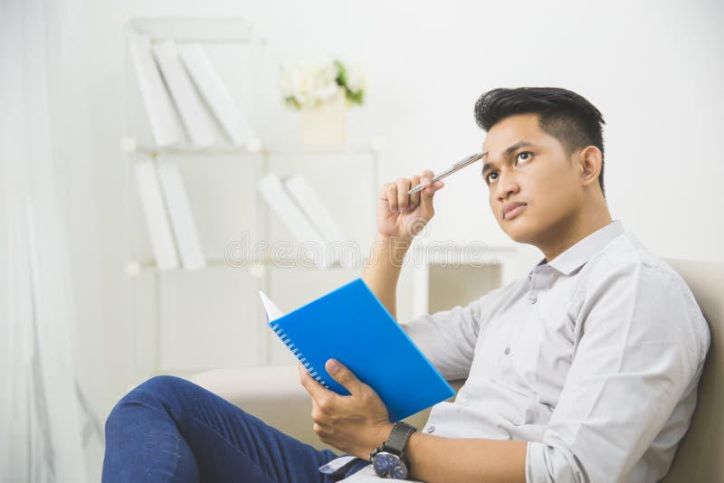 Young Man Thinking while Writing on a Book Stock Photo - Image of ...