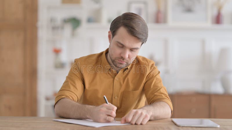 Young Man Thinking while Writing on Paper in Office Stock Image - Image ...