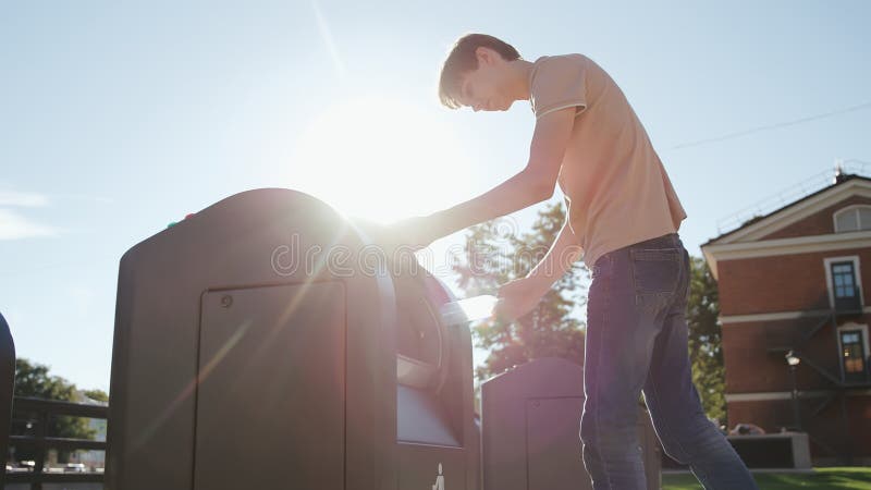Young Man Throw Away an Empty Plastic Bottle into a Trash Bin Outdoors ...
