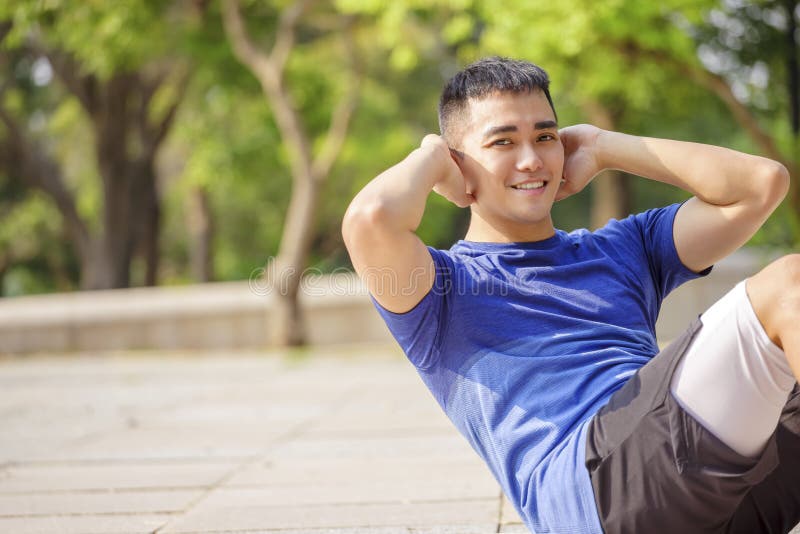 Young Man Training and Doing Sit Ups in Park Stock Image - Image of ...