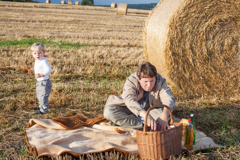 Young Man and Two Little Boys Making Picnic on Hay Field Stock Photo ...