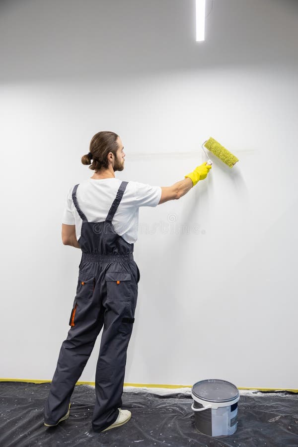 Young Man in Uniform Painting the Wall and Looking Busy Stock Photo ...