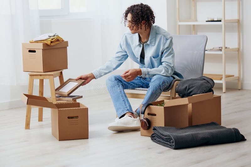 A Young Man Unpacking Things from Boxes in the Room Interior Stock ...