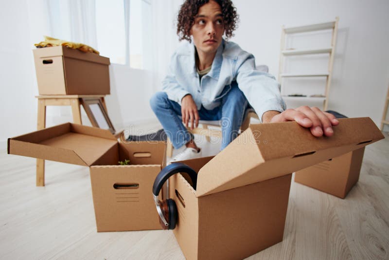 A Young Man Unpacking Things from Boxes in the Room Sorting Things Out ...