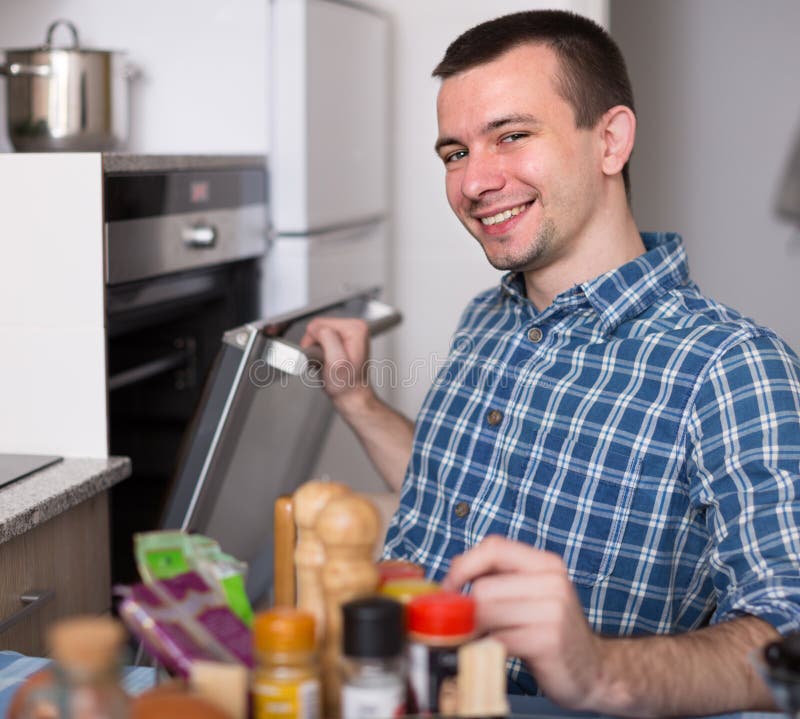 Young Man Uses Oven in Kitchen at Home Stock Photo - Image of males ...