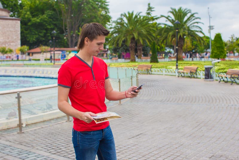 Young Man Using Cell Phone with Map Walking in Big Stock Image - Image ...
