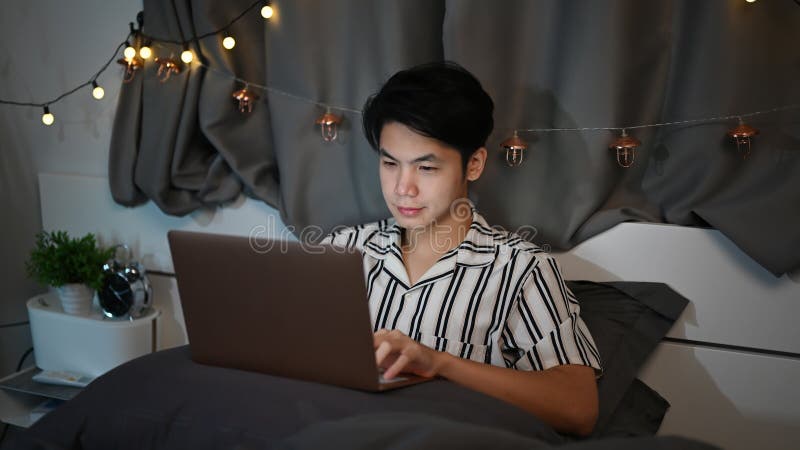 Young Man Using Computer Laptop in His Bed at Night. Stock Photo ...