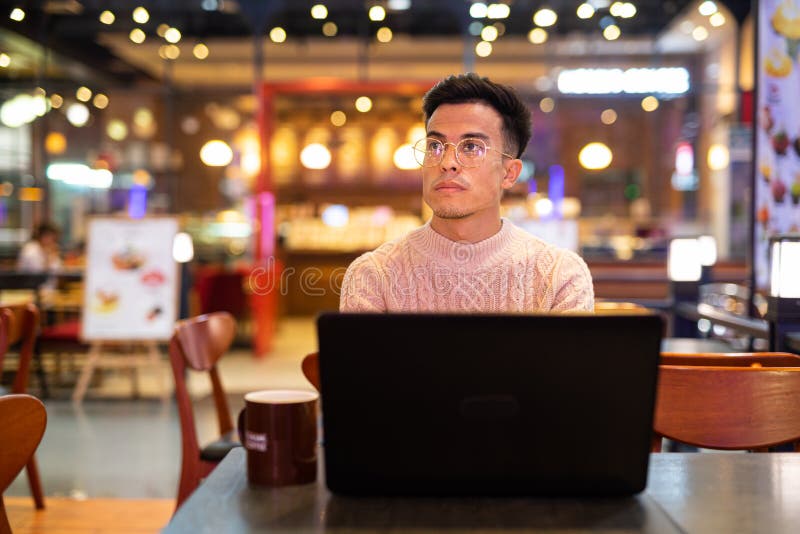 Young Man Using Laptop Computer at Coffee Shop while Thinking Stock ...