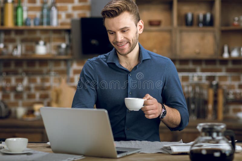 Young Man Using Laptop while Drinking Coffee at Home Stock Photo ...