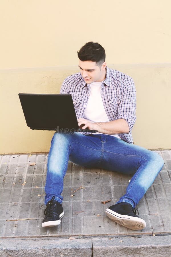 Young man using laptop stock photo. Image of young, sitting - 85026564