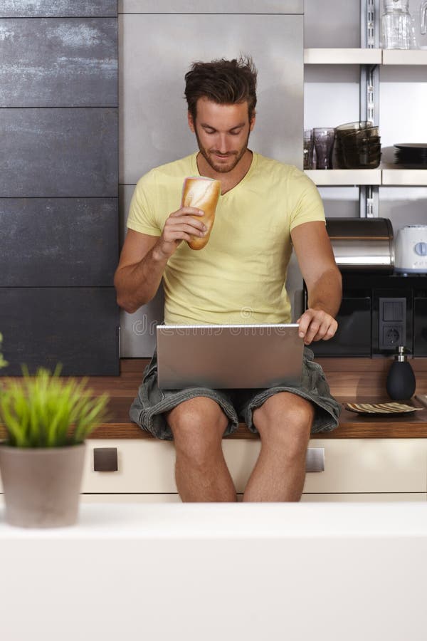 Young Man Using Laptop on Kitchen Counter Stock Photo - Image of face ...