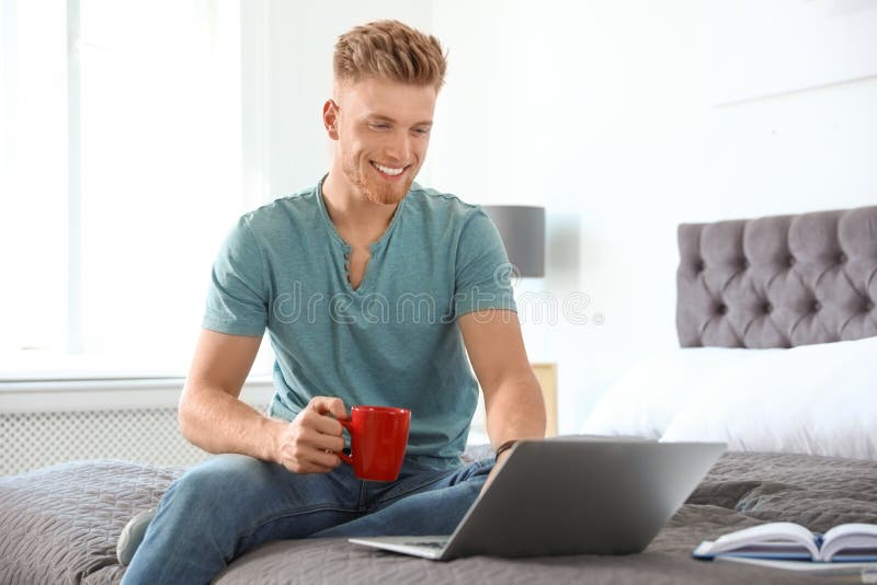 Young Man Using Laptop while Sitting on Bed Stock Image - Image of ...