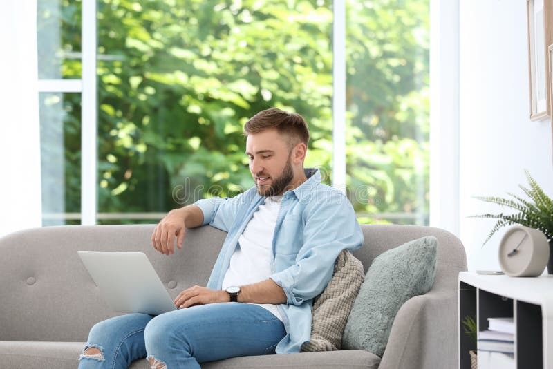 Young Man Using Laptop while Sitting on Sofa Stock Image - Image of ...