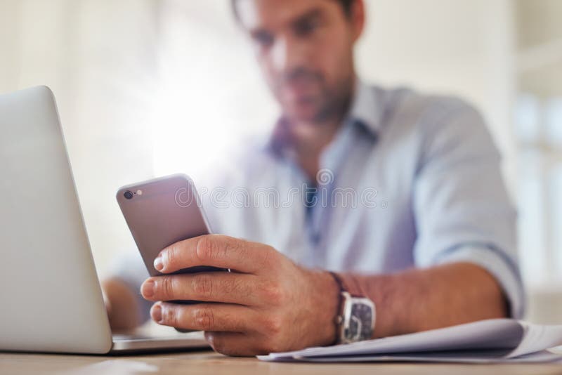 Young Man Using Mobile Phone while Working on Laptop Stock Image ...