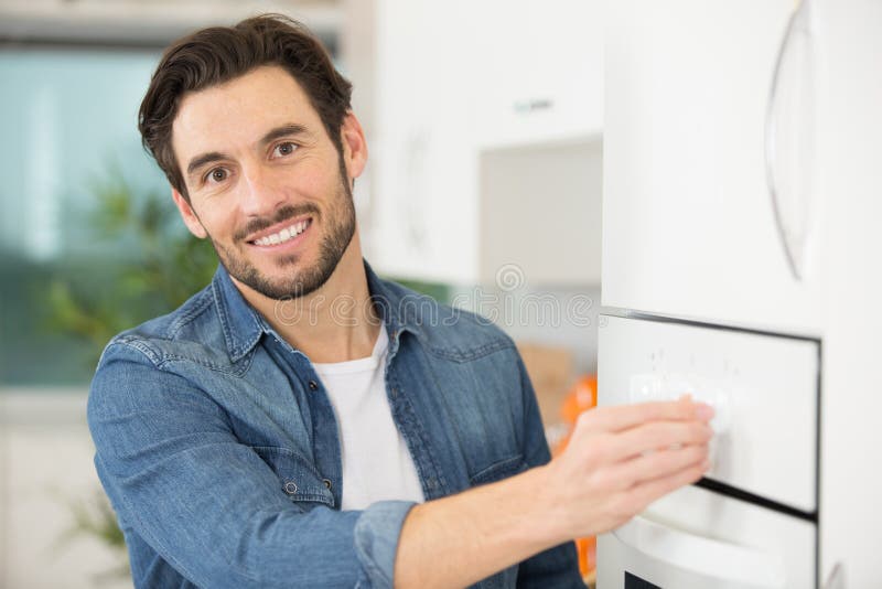 Young man using oven stock image. Image of household - 260781779