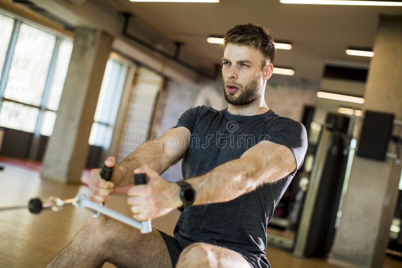 Young Man Using Seated Row Machine in the Gym Stock Image - Image of ...